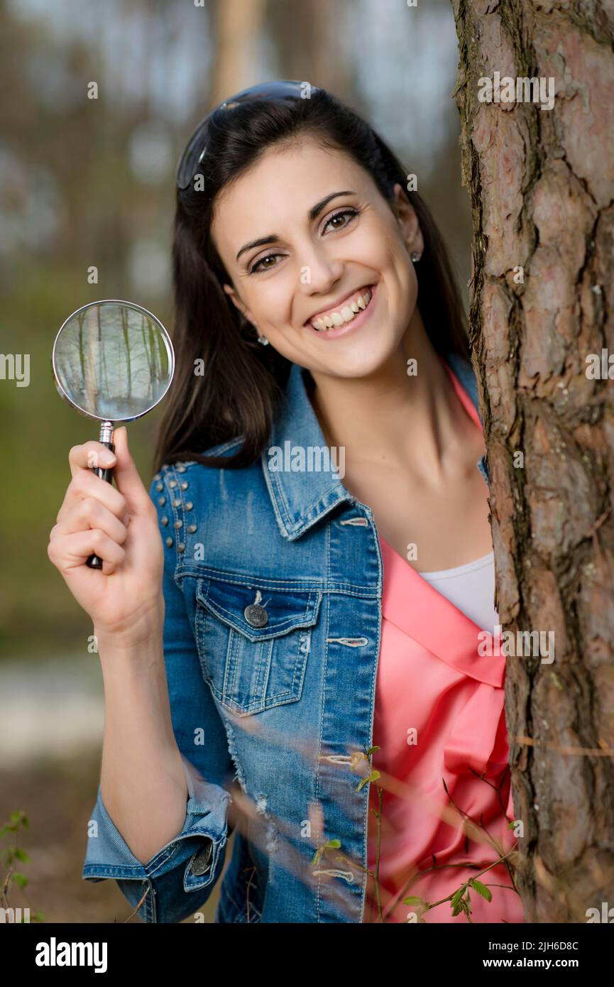 Woman looks at tree trunk under the magnifying glass Stock Photo - Alamy