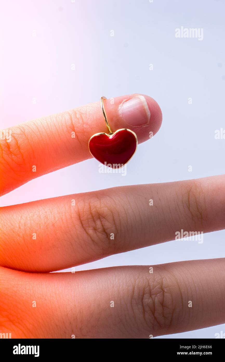 Red color heart shape earring in hand on white Stock Photo - Alamy