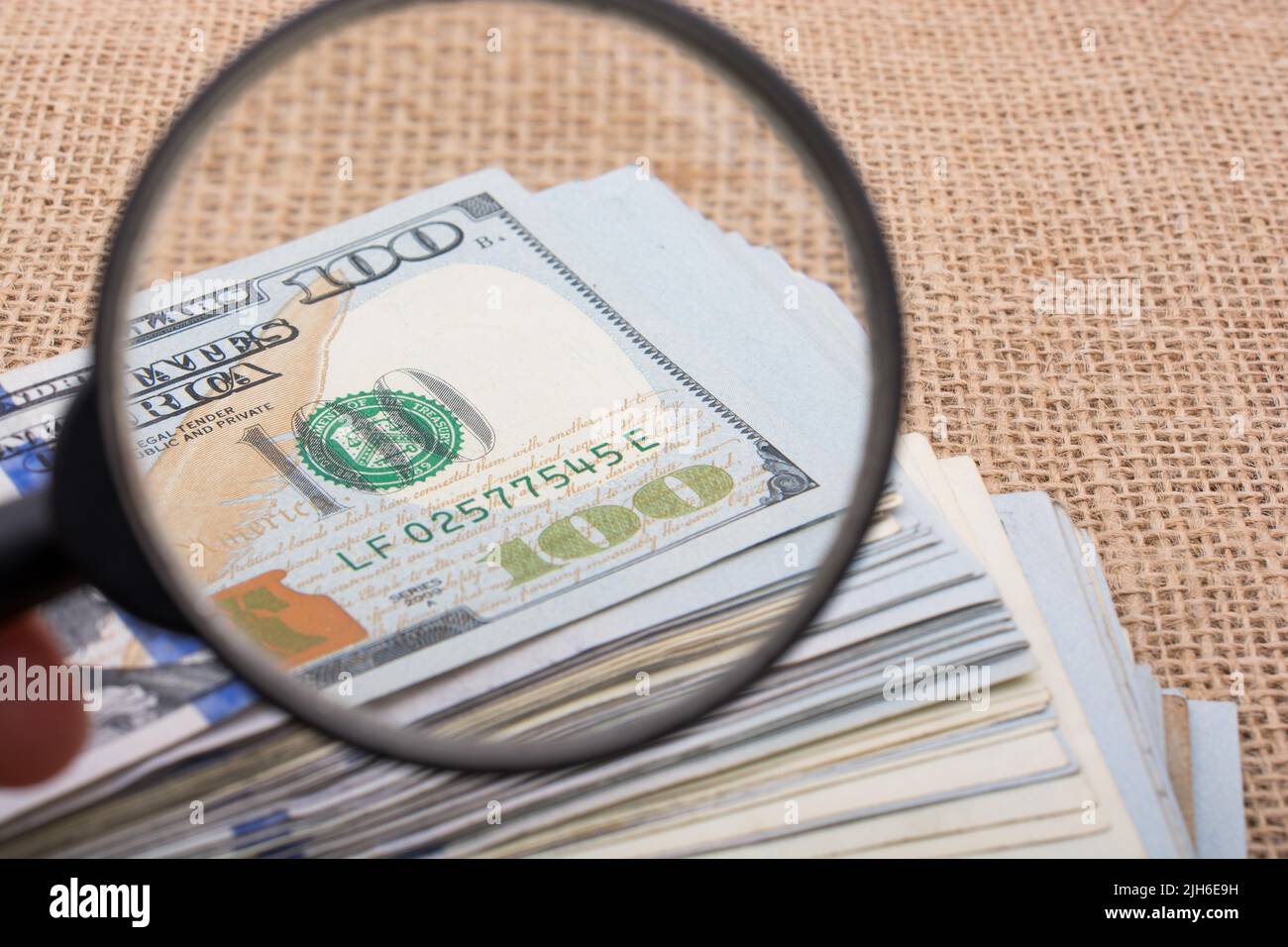 Magnifying glass is held over the banknote bundle of US dollar Stock ...