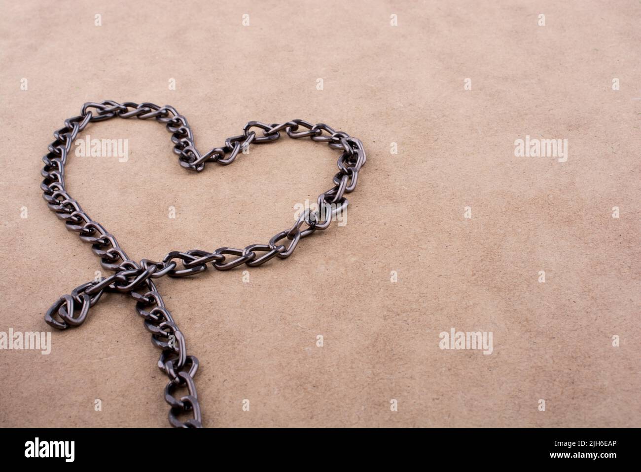 Chain form a heart shape on a brown background Stock Photo - Alamy