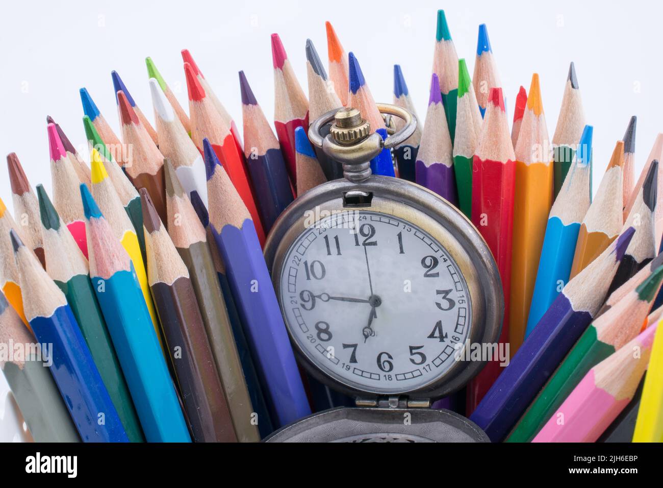 Retro style classic pocket watch and color pencils on white background ...