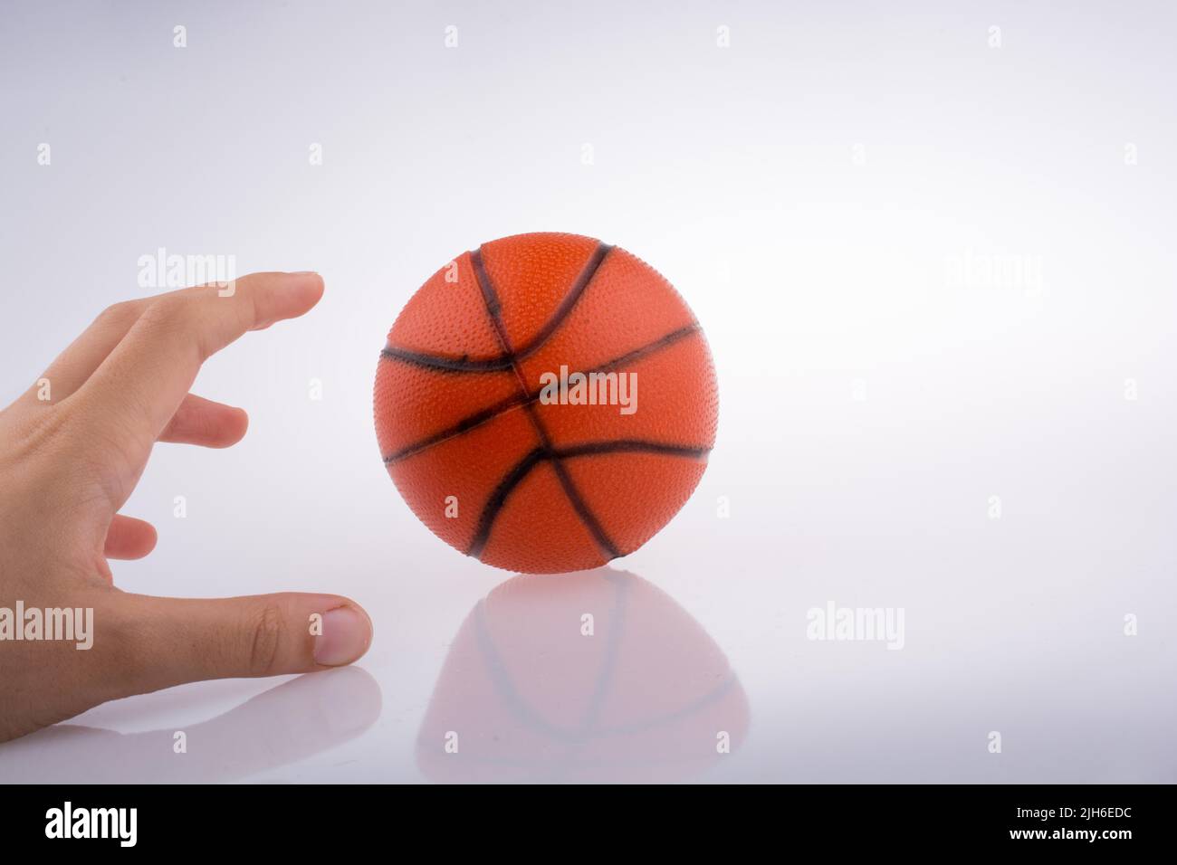 Hand holding an orange basketball model on a white background Stock ...