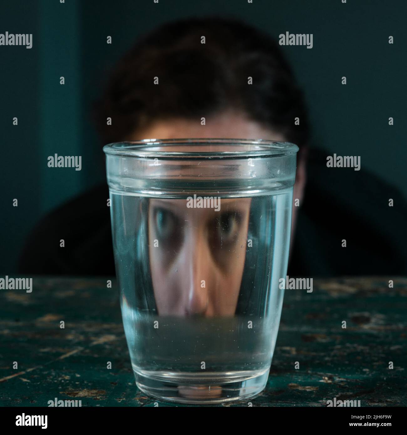 Curious face of a woman reflected in a water glass Stock Photo - Alamy
