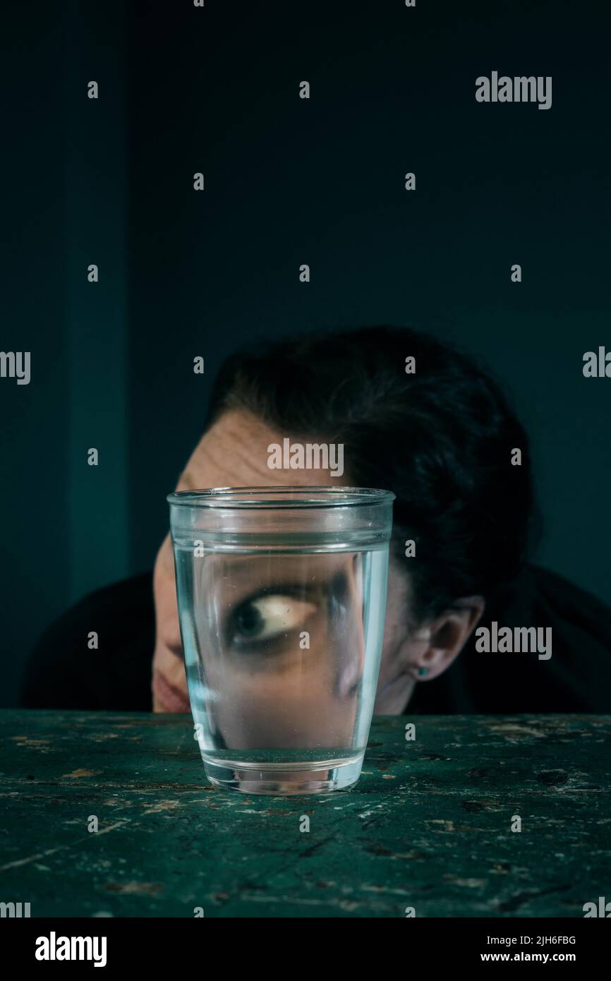 Face of a woman, eye reflected in a water glass Stock Photo - Alamy