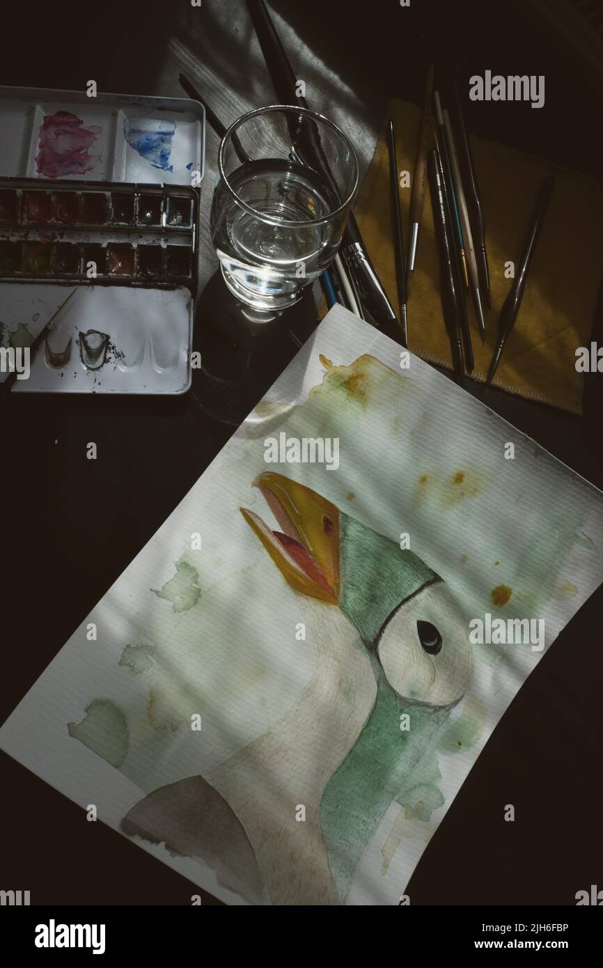 Painted goose, watercolour painting with water glass, brushes and ...