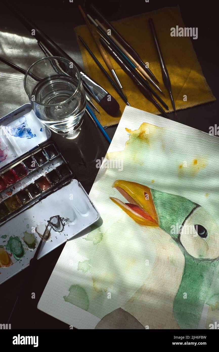 Painted goose, watercolour painting with water glass, brushes and ...