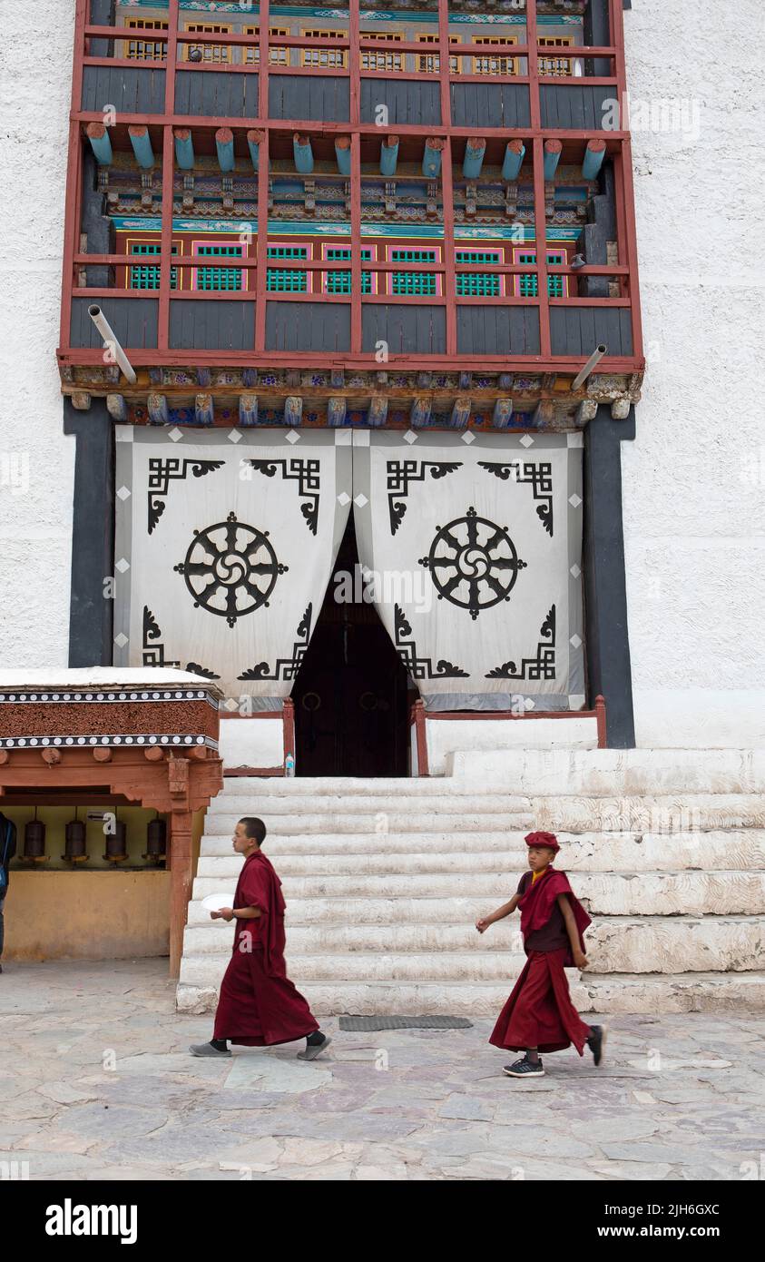 Two novices walk across the monastery courtyard, the entrance portal at ...
