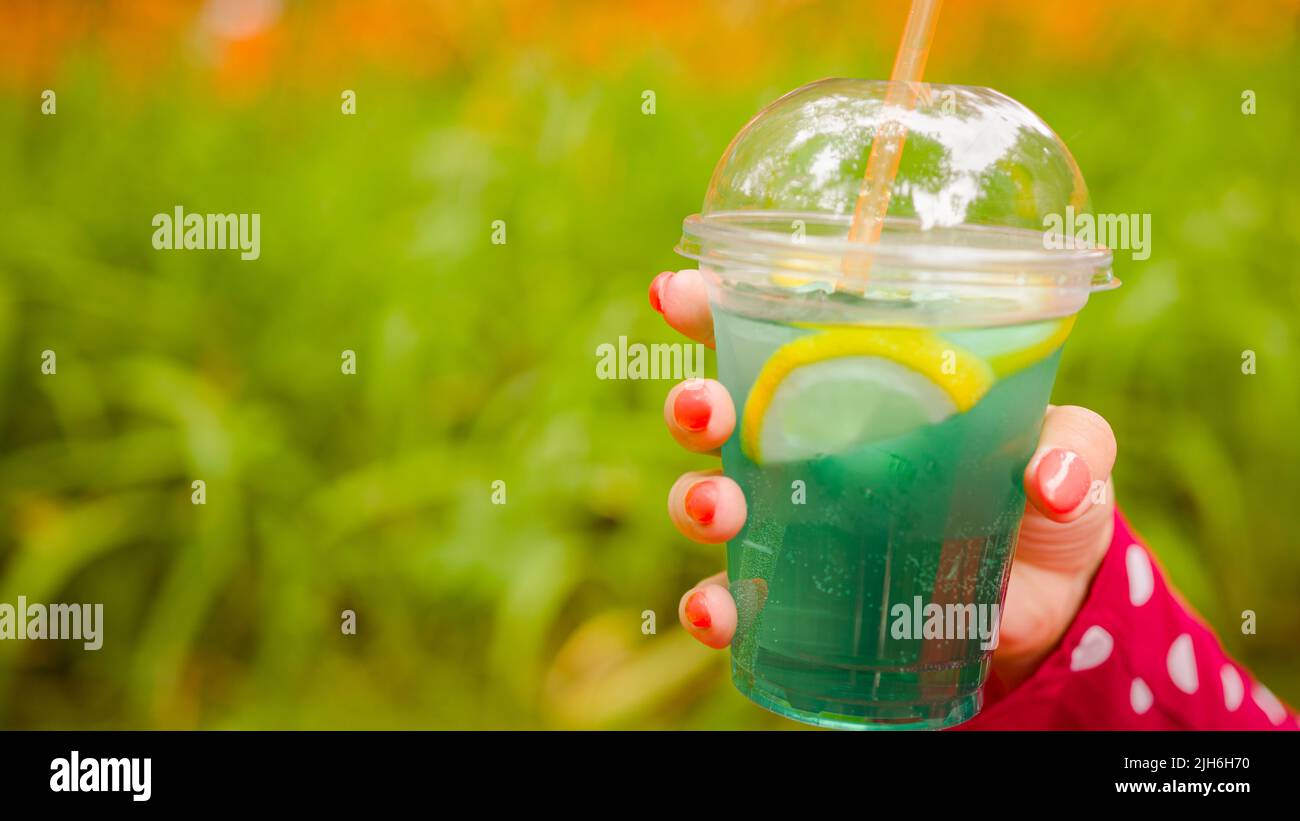 Cool lemonade in transparent cup with straw in hands of anonymous woman ...
