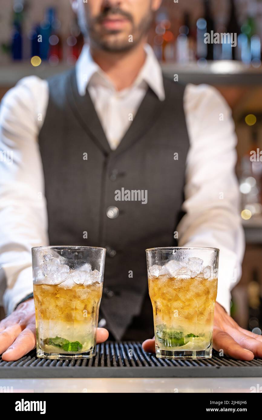 Barman serves Mojito in night club adding ingredients and creating ...