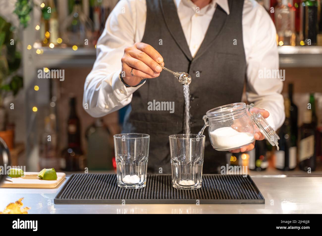 Elegant barman making cocktail Mojito in night club adding ingredients ...