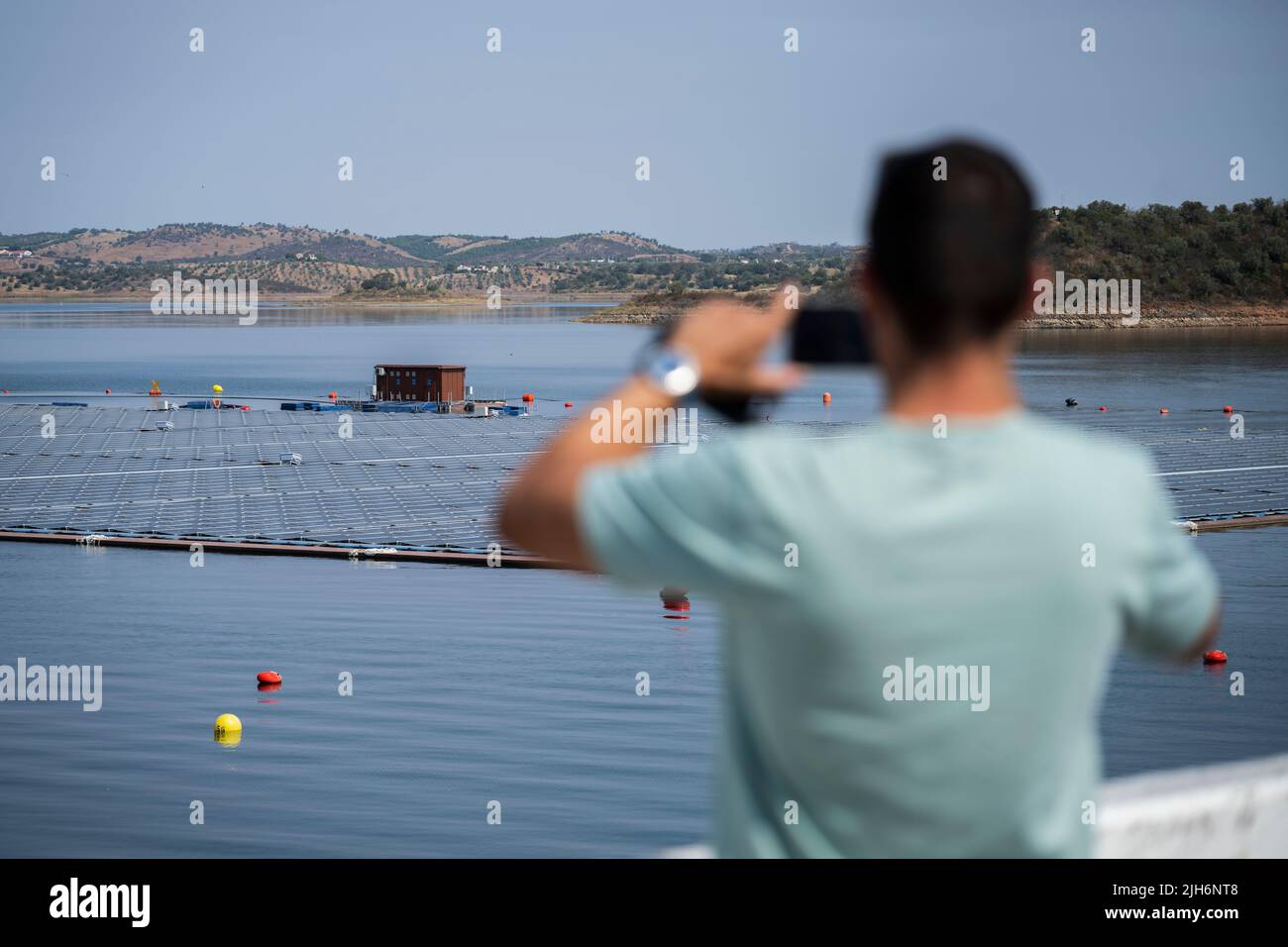 A tourist is seen taking photos of the floating solar power plant in ...