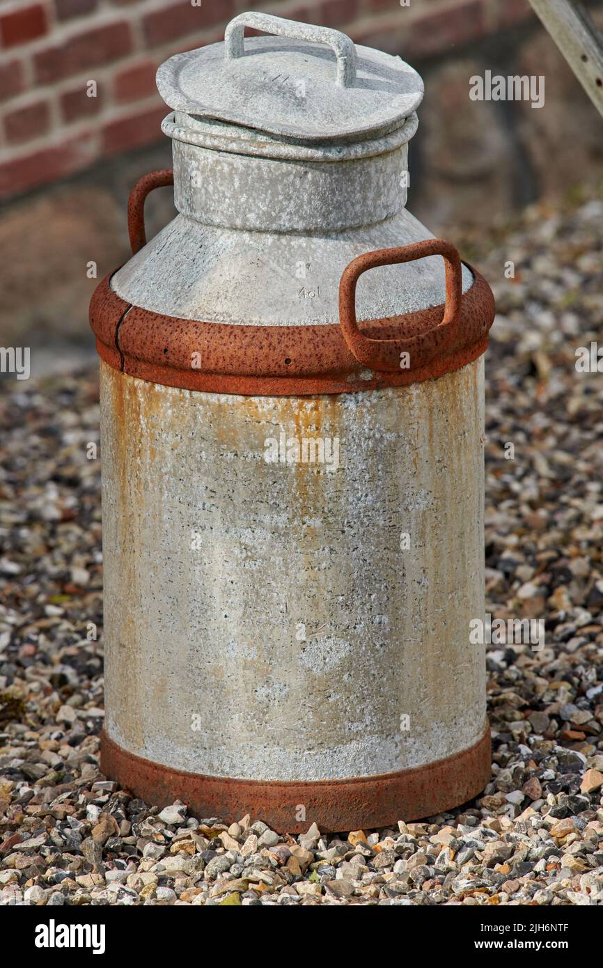 An old rusted metal milk can on the ground from above. An antique dairy ...