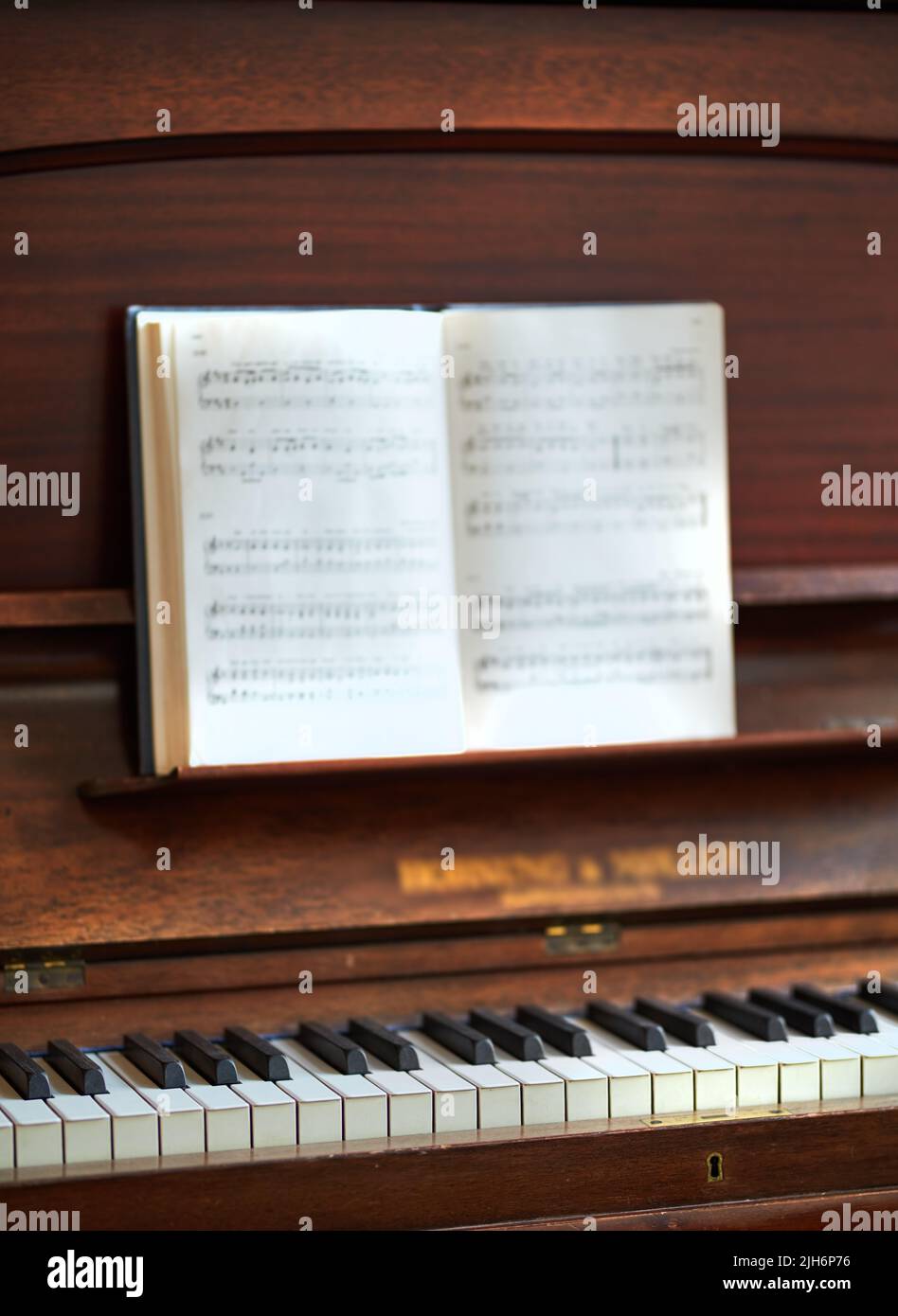 Closeup of a vintage piano and keyboard with a sheet music book. An ...