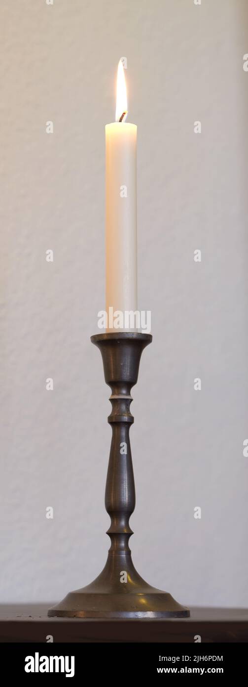 One lit candle on a table at home for decoration and warmth. Beautiful ...