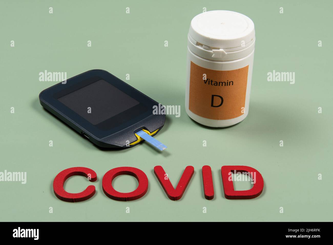 device to measure blood glucose, vitamin D box and the word Covid ...