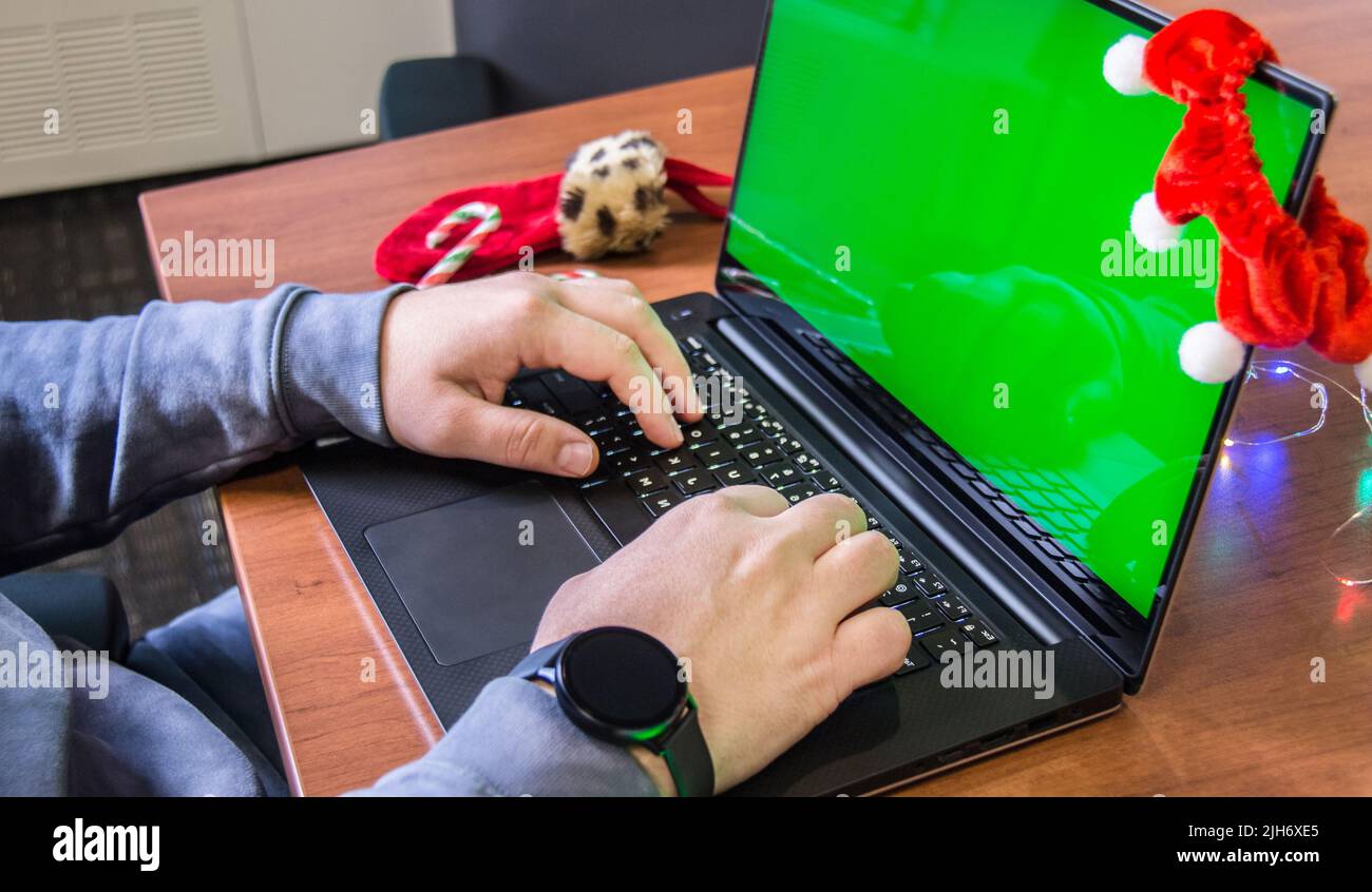 Closeup man hands typing on laptop keyboard with empty green screen and ...