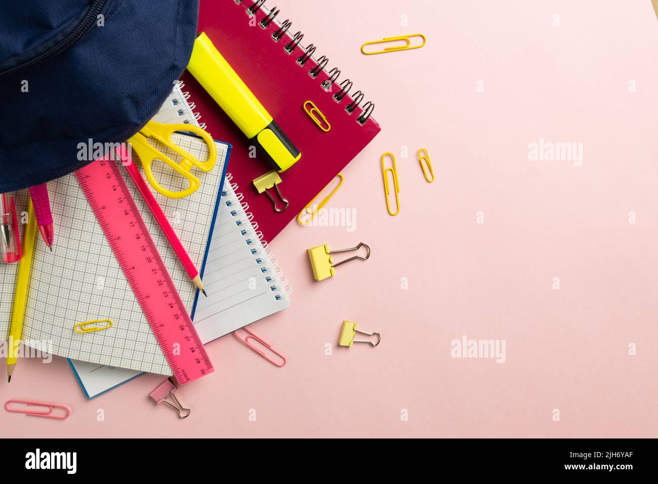 Composition of notebooks and school equipment in navy case on pale pink ...