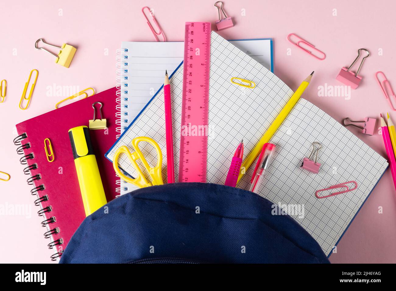 Composition of notebooks and school equipment in navy case on pale pink ...