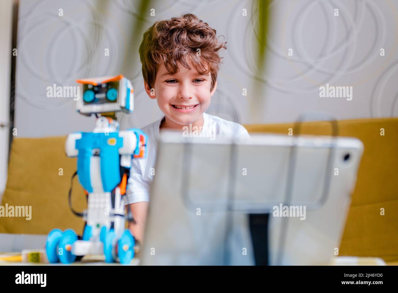 Kid collects robot from plastics details and programmed on tablet ...