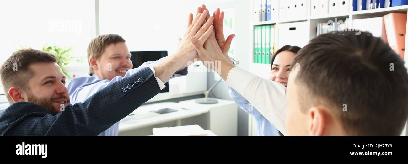 Witty colleagues performing high five gesture in order to celebrate ...