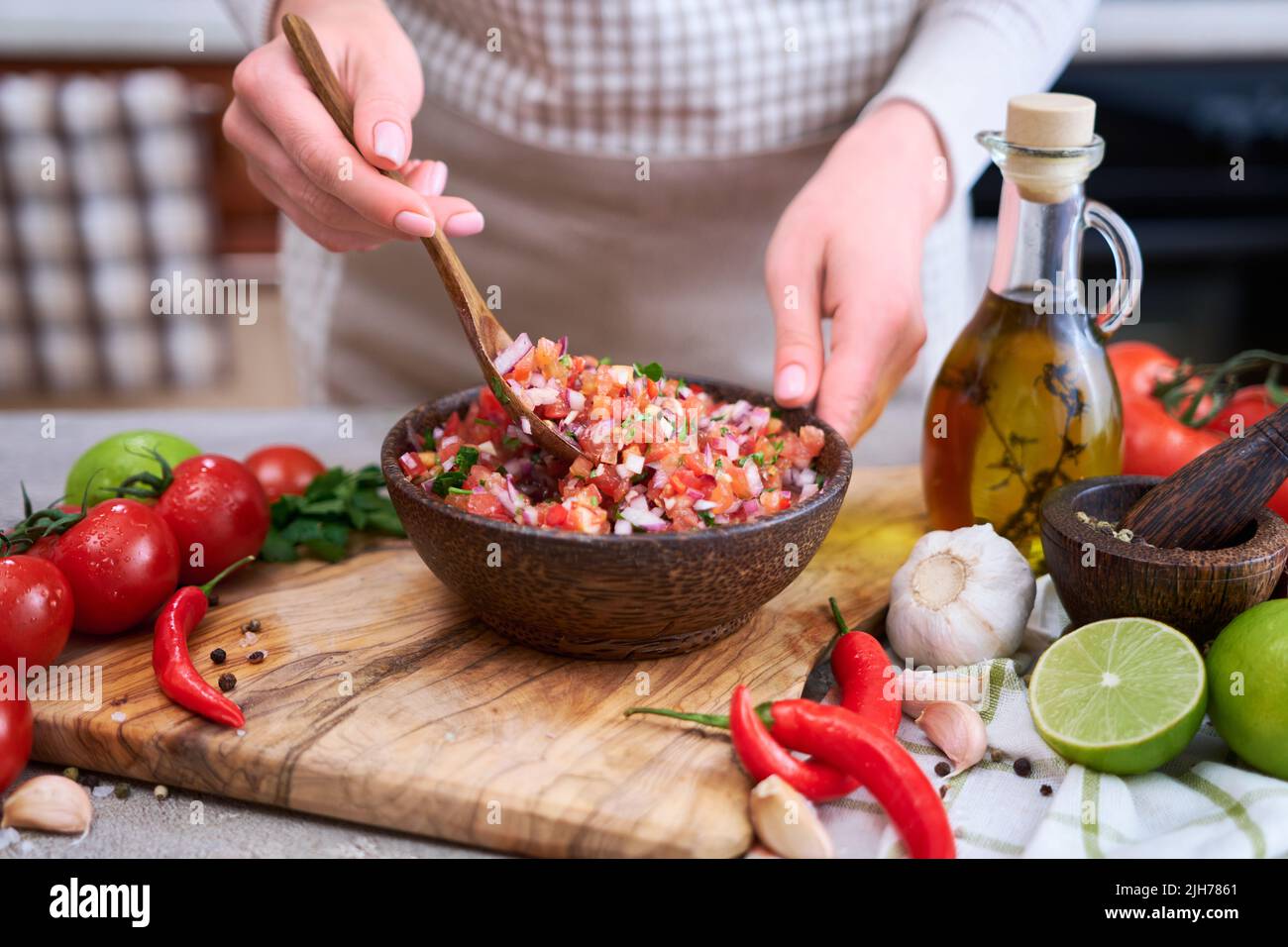 making salsa dip sauce - woman mixing chopped ingredients in wooden ...