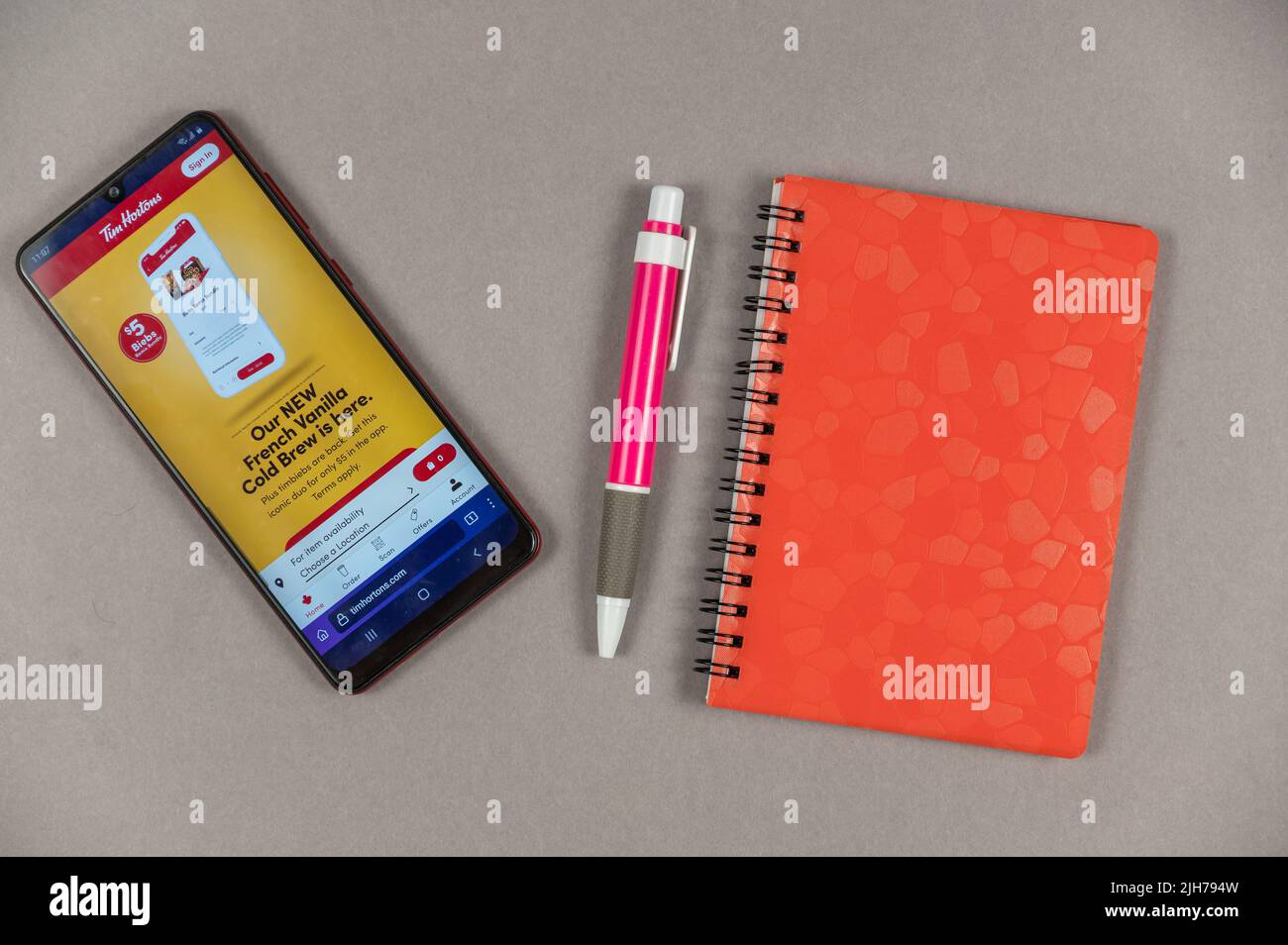 Red notepad, pen and smartphone on gray. Tim Hortons' lead page is on ...