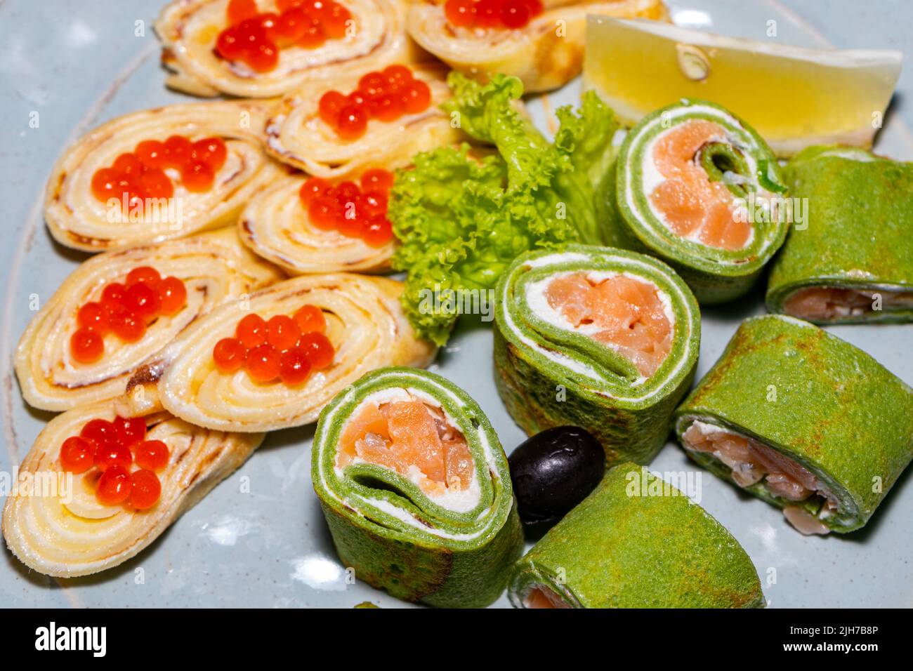 Some green sushi with red fish and pancakes with red caviar close-up ...