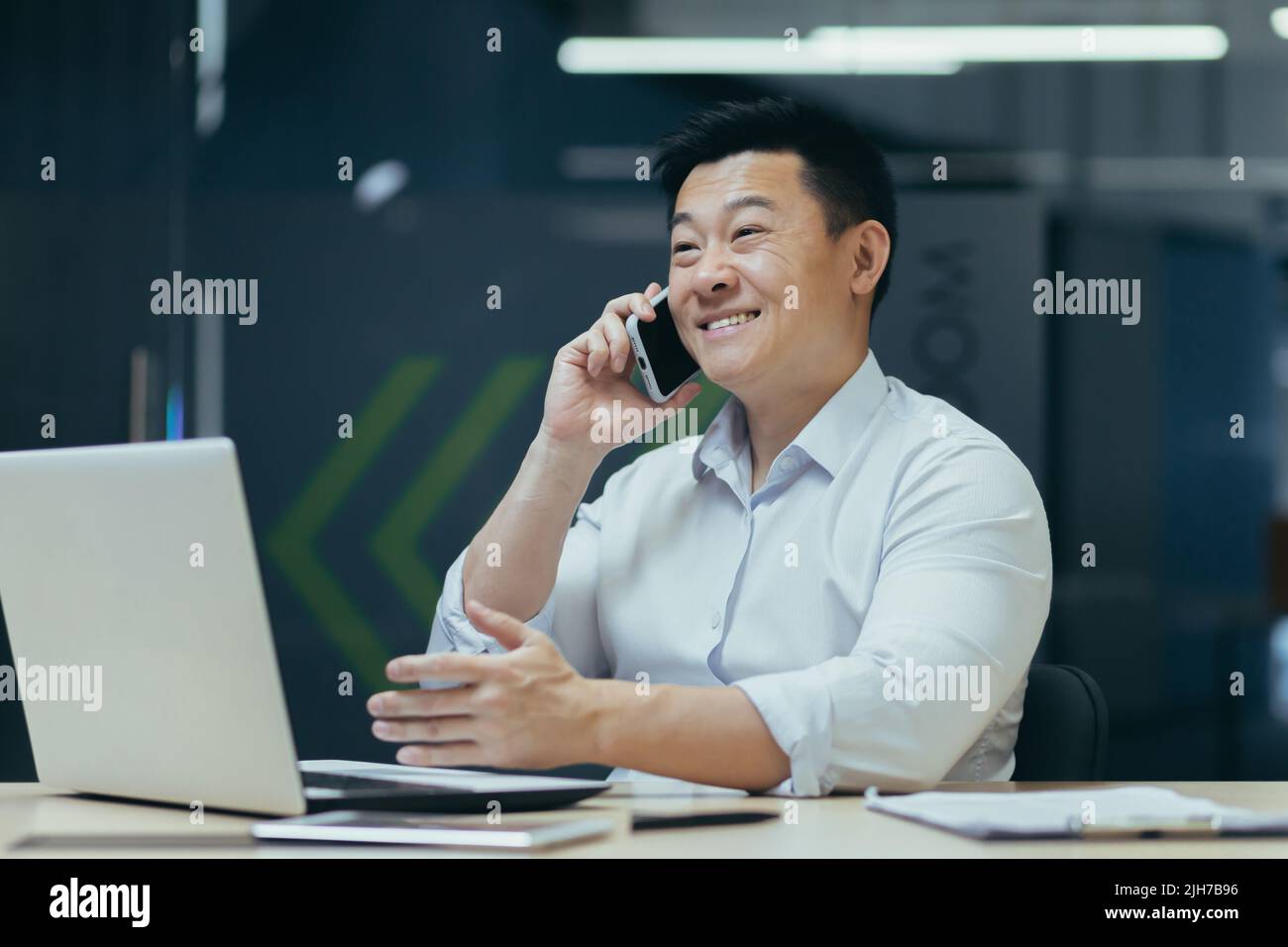 Online store. A young Asian salesman talks on the phone with customers ...