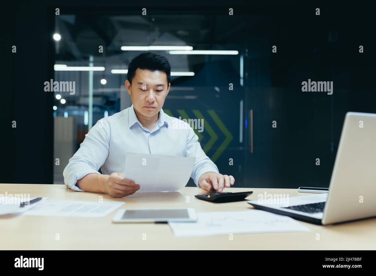 Young Asian male accountant working with documents and calculator ...