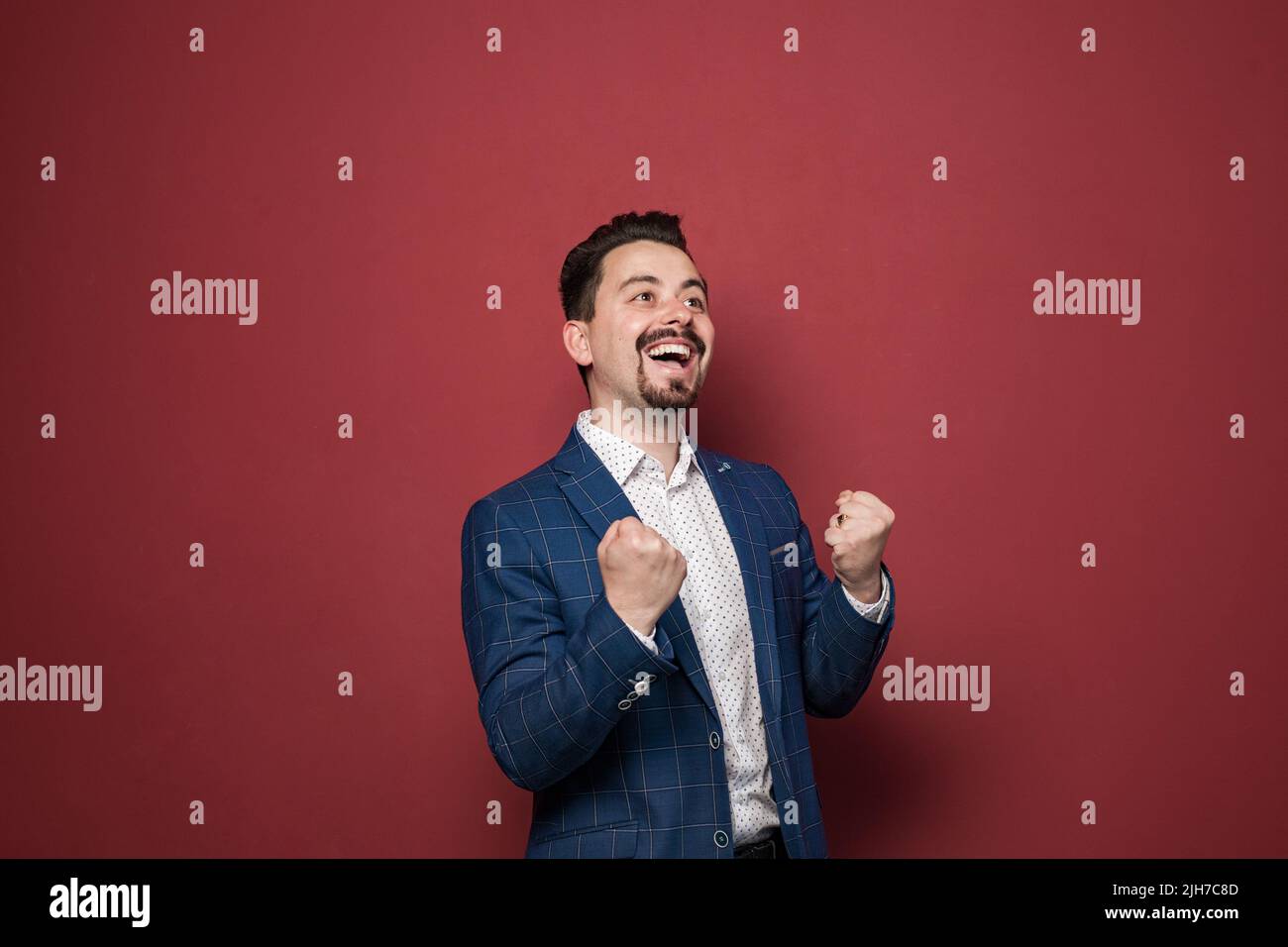 Celebrating success. Portrait of a happy young man in business suit ...
