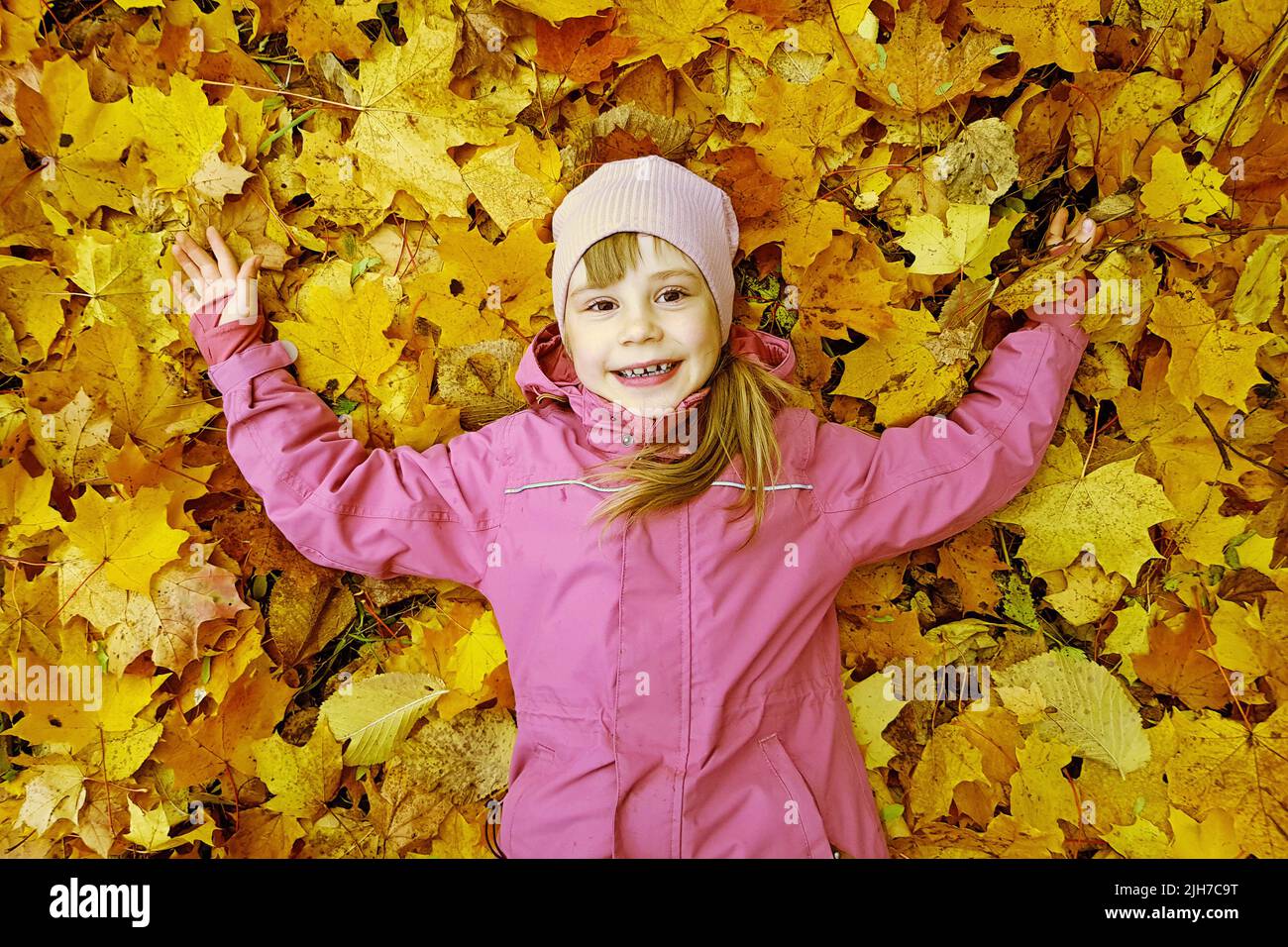 Little kid girl lying on colorful fall leaves background in autumn park ...
