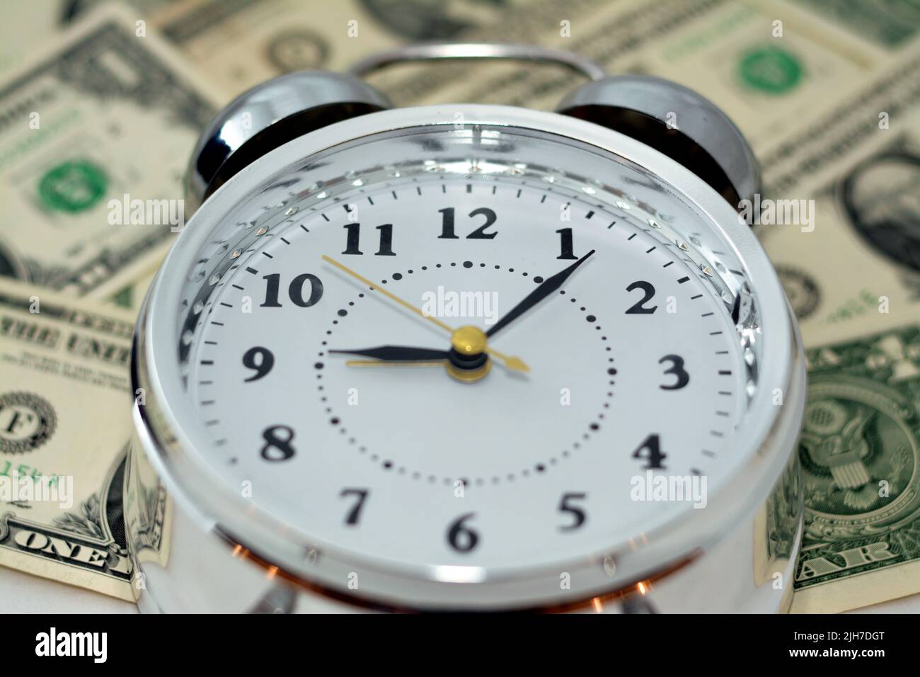 An alarm clock on a background of blurred American money banknote ...