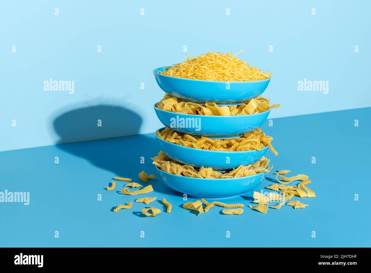 Plates with uncooked pasta stacked one above each other on a blue table ...