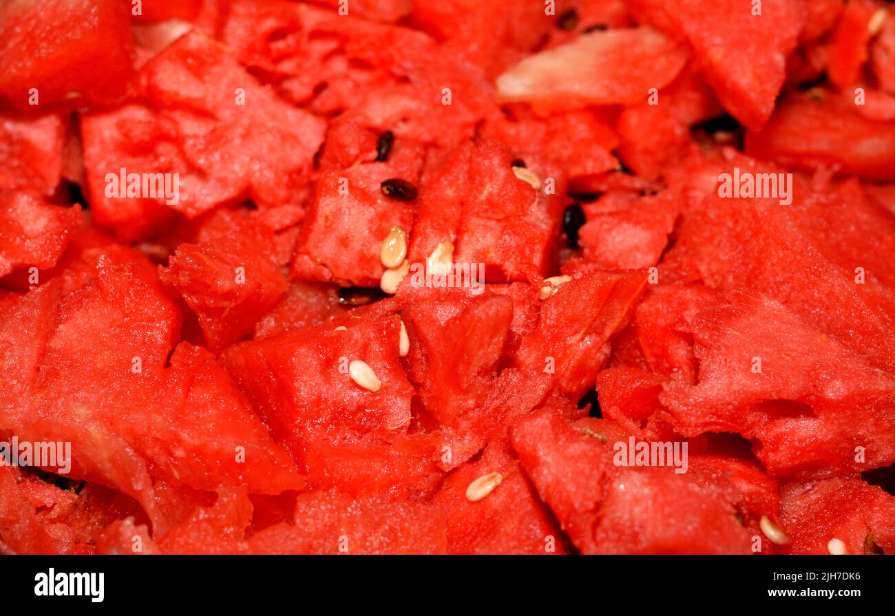 A closeup of a pile of watermelon fruit cuts into small pieces with ...
