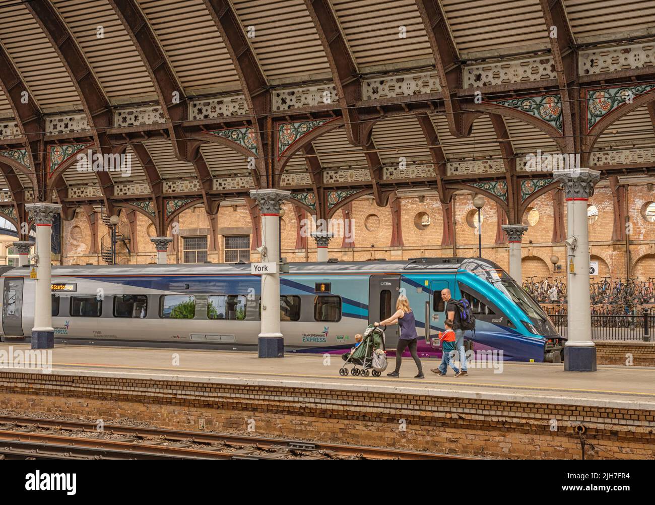 A family walks past a waiting train at a railway station platform. The ...
