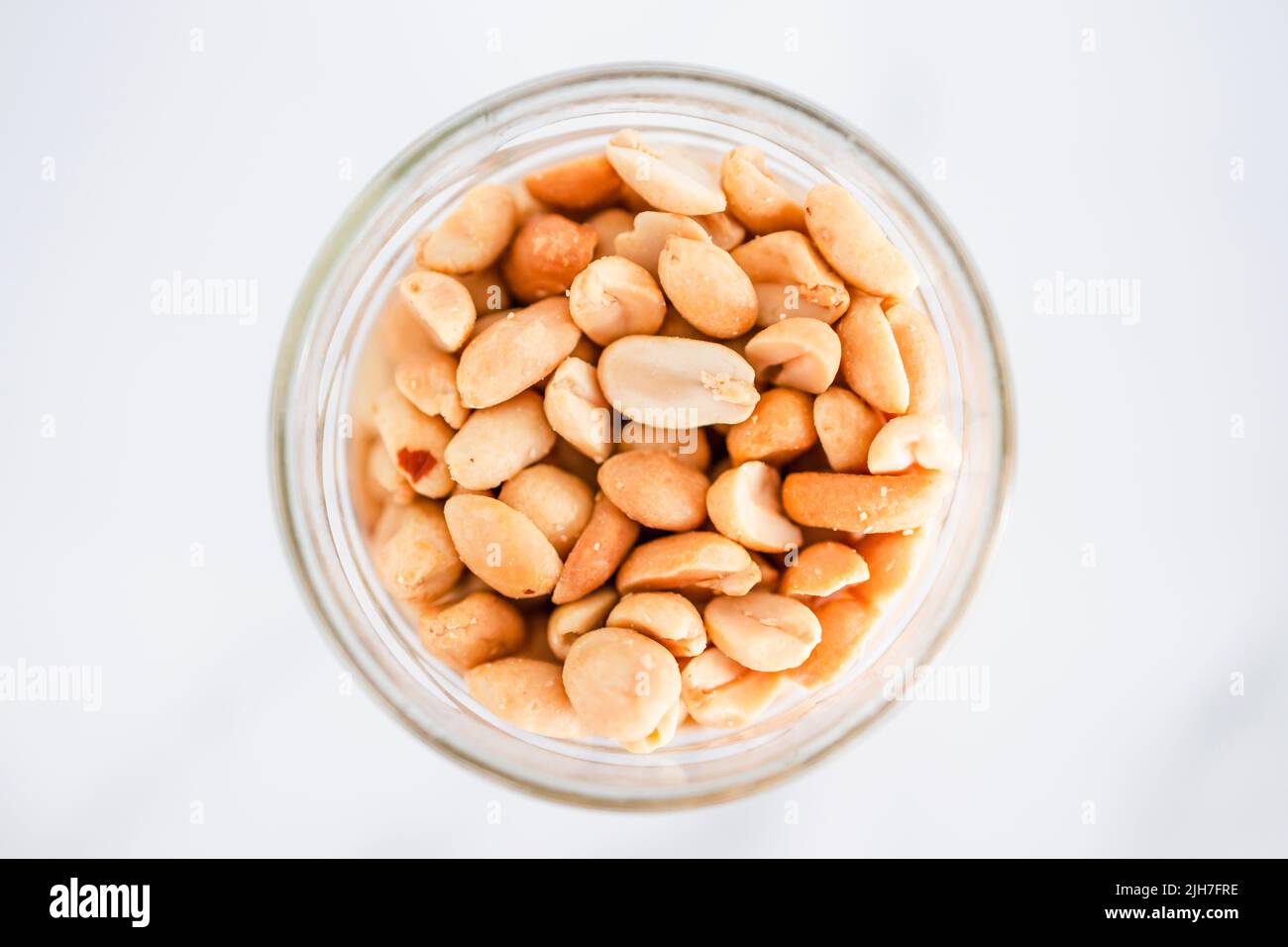 glass jar of peanuts on white marble background, natural healthy pantry ...