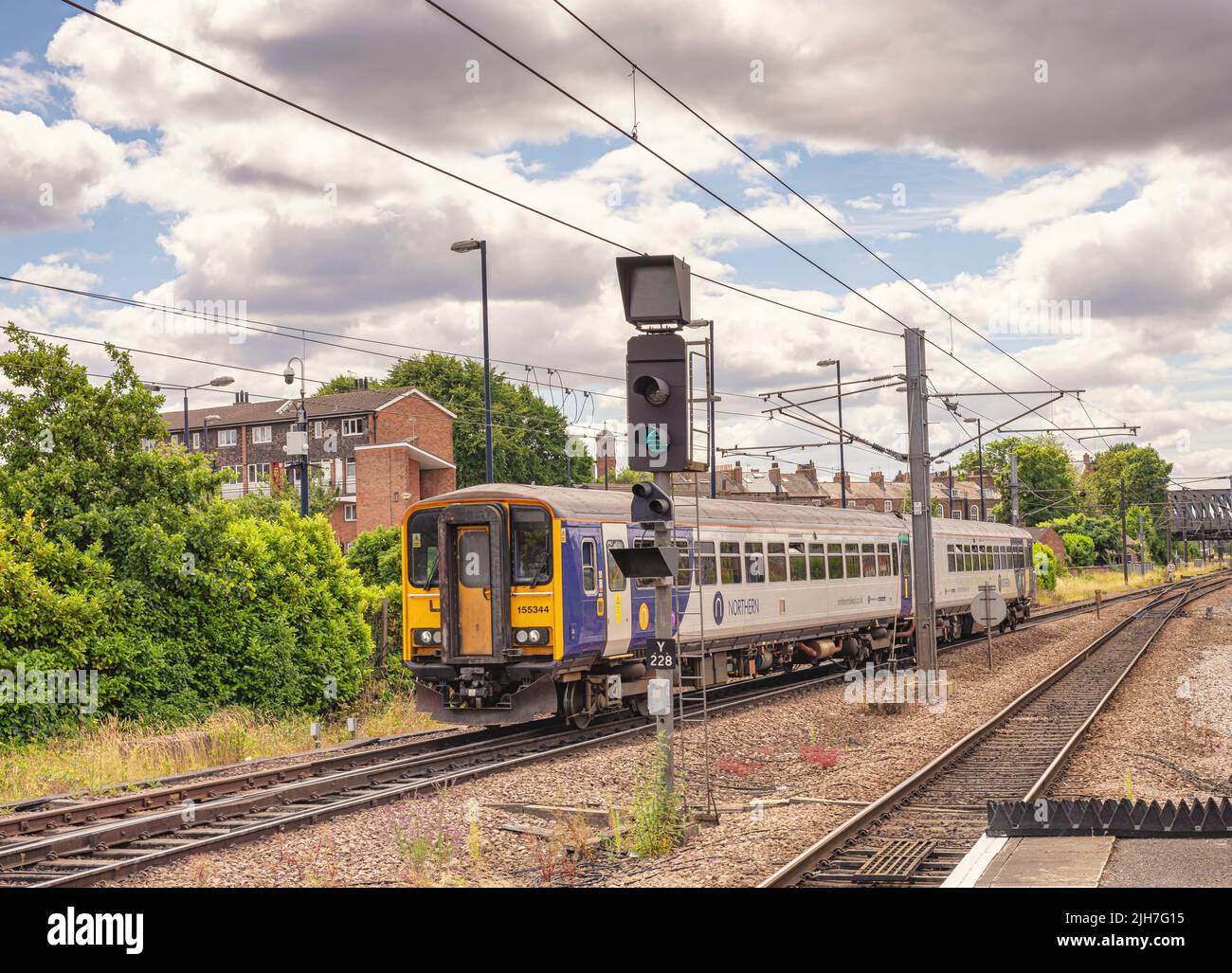 A train approaches a railway station with buildings at one side. A ...