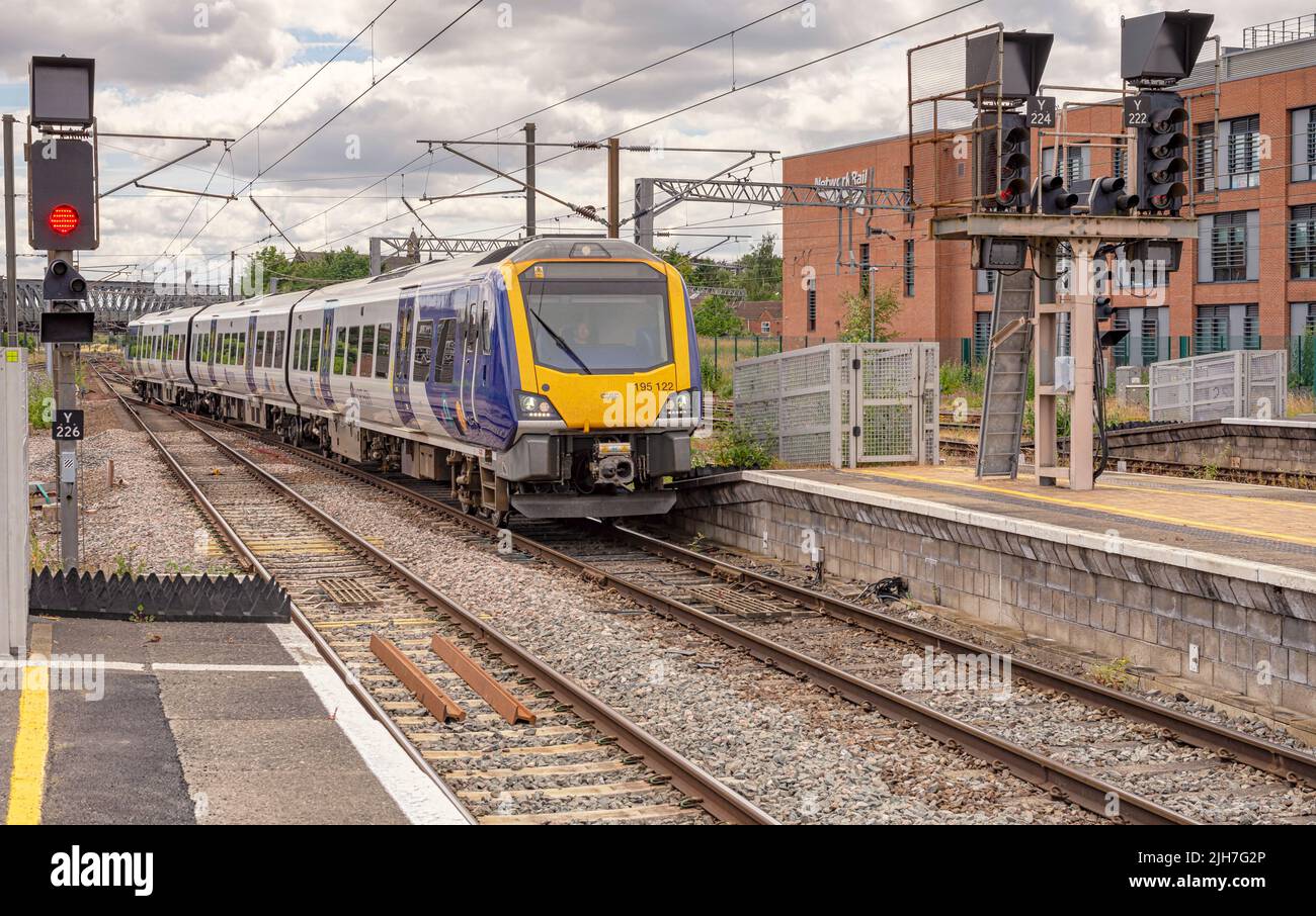 A train approaches a railway station with buildings at one side. A ...
