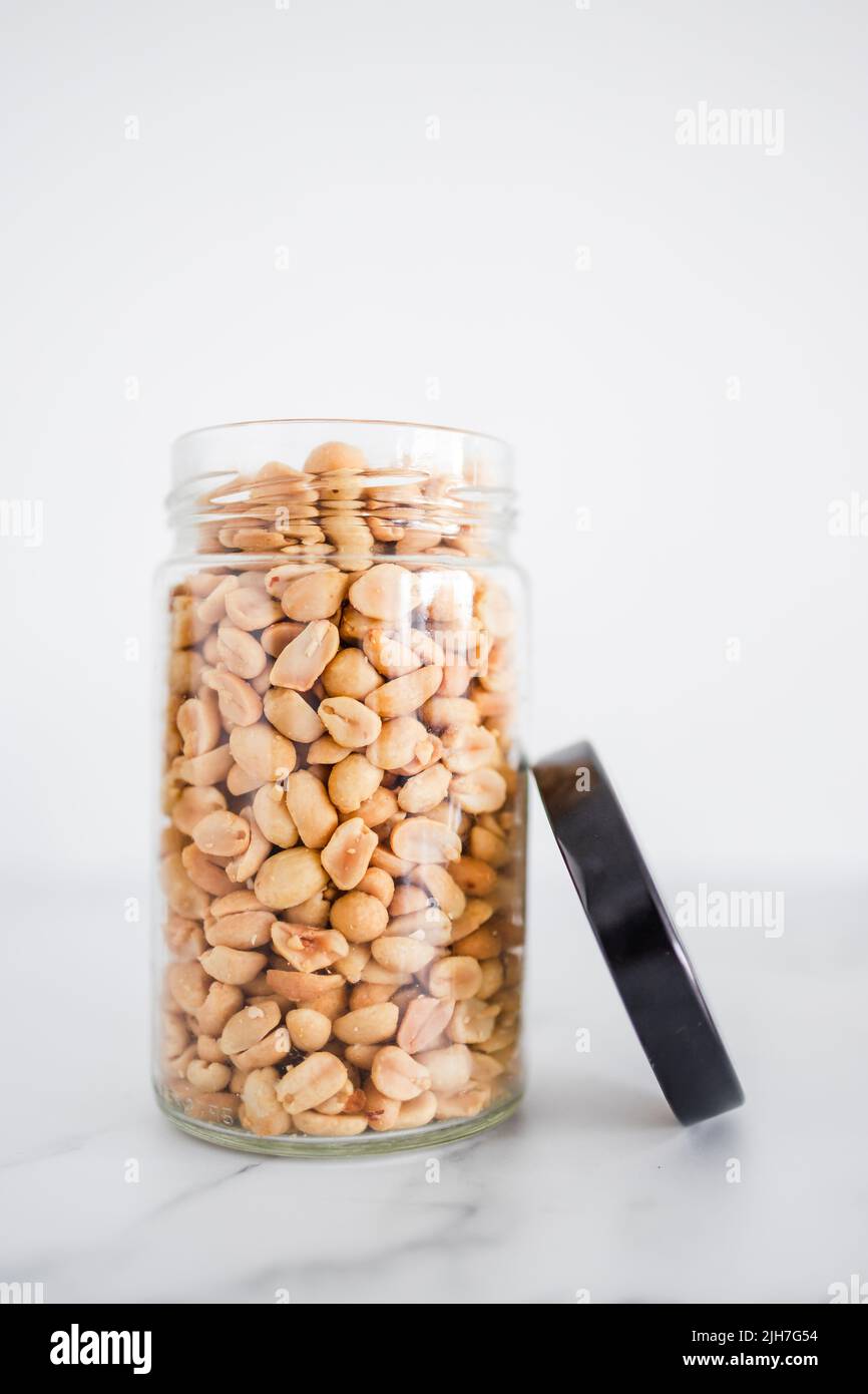 glass jar of peanuts on white marble background, natural healthy pantry ...