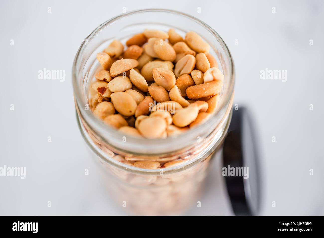 glass jar of peanuts on white marble background, natural healthy pantry ...