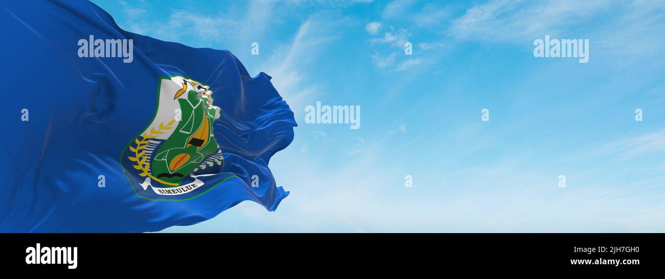 official flag of Regency Simeulue Indonesia at cloudy sky background on sunset, panoramic view ...