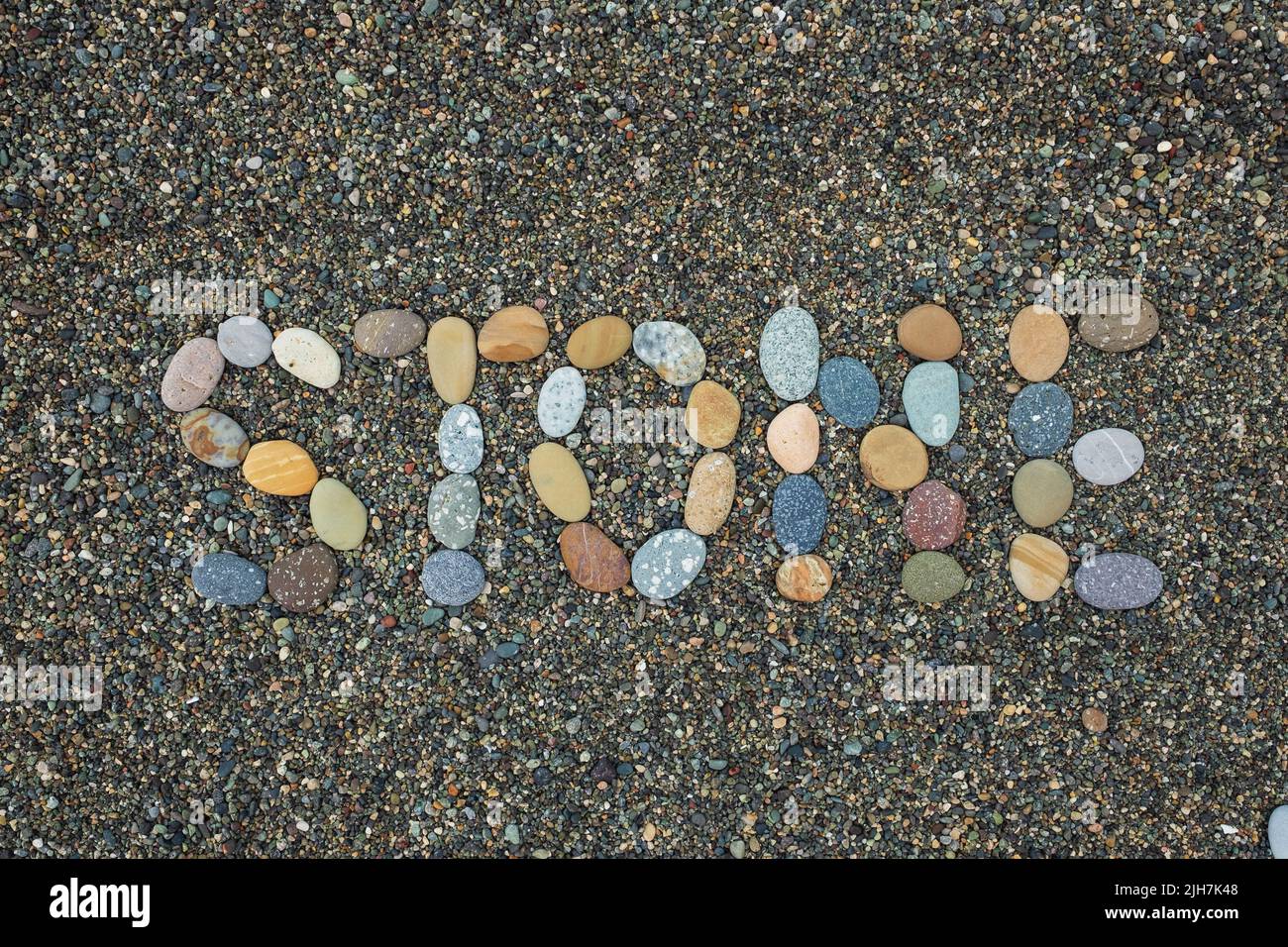 Text stone made from stones on sandy beach Stock Photo - Alamy