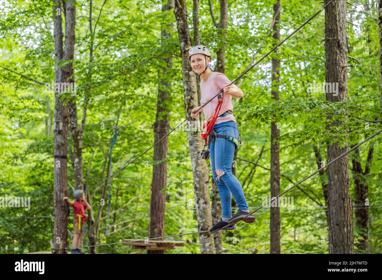Mother and son climbing in extreme road trolley zipline in forest on ...