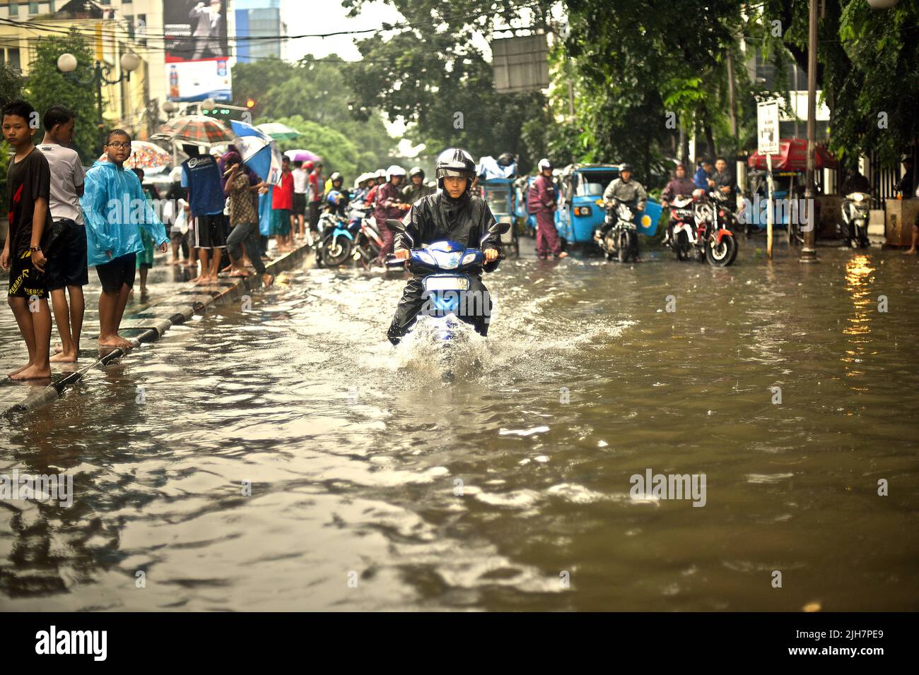 A motorist riding through flooded street in Jakarta, after a continuous ...