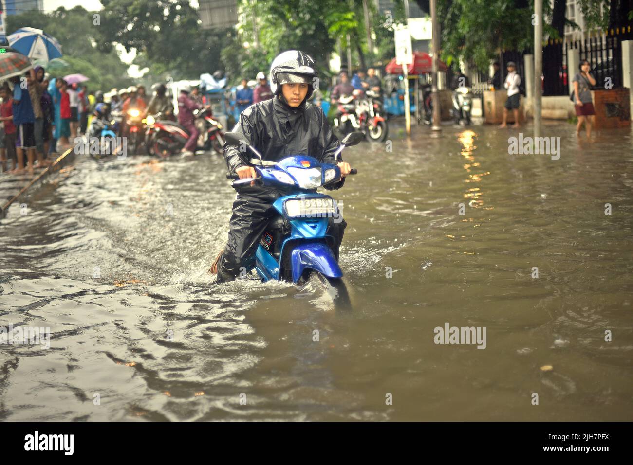 A motorist riding through flooded street in Jakarta, after a continuous ...