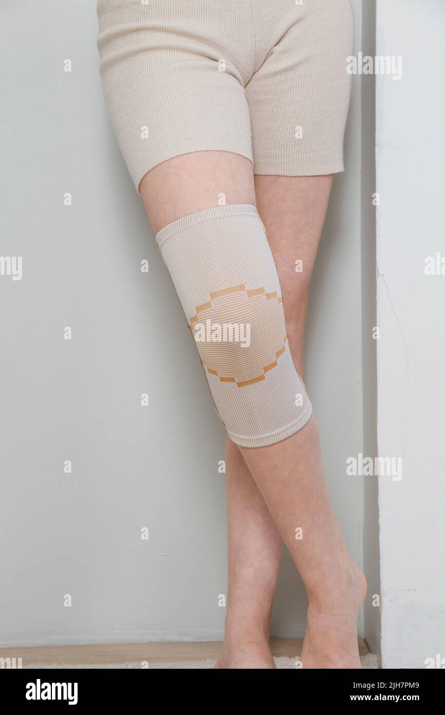 Knee support brace on a woman leg. girl in an orthosis in the interior ...