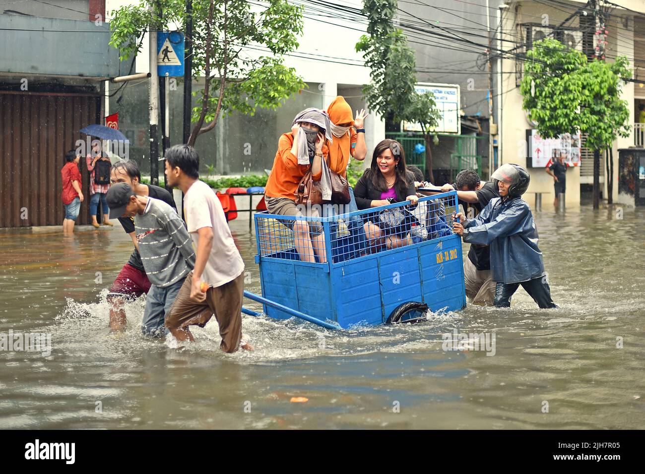 Men helping women to travel through a flooded street by a cart in Jakarta, after a continuous ...