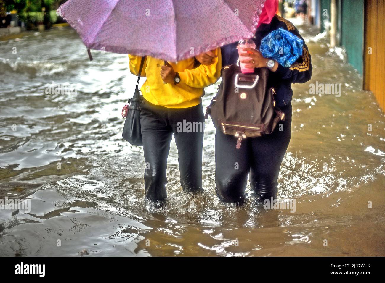 Women walking on a flooded walkway in Jakarta, after a continuous rain ...