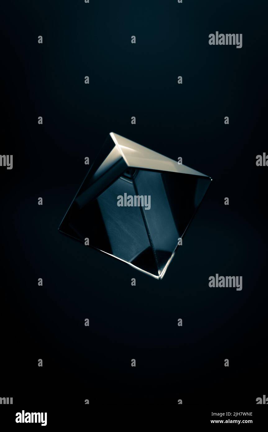 Abstract shiny pyramid on black background. Glass pyramid still life ...