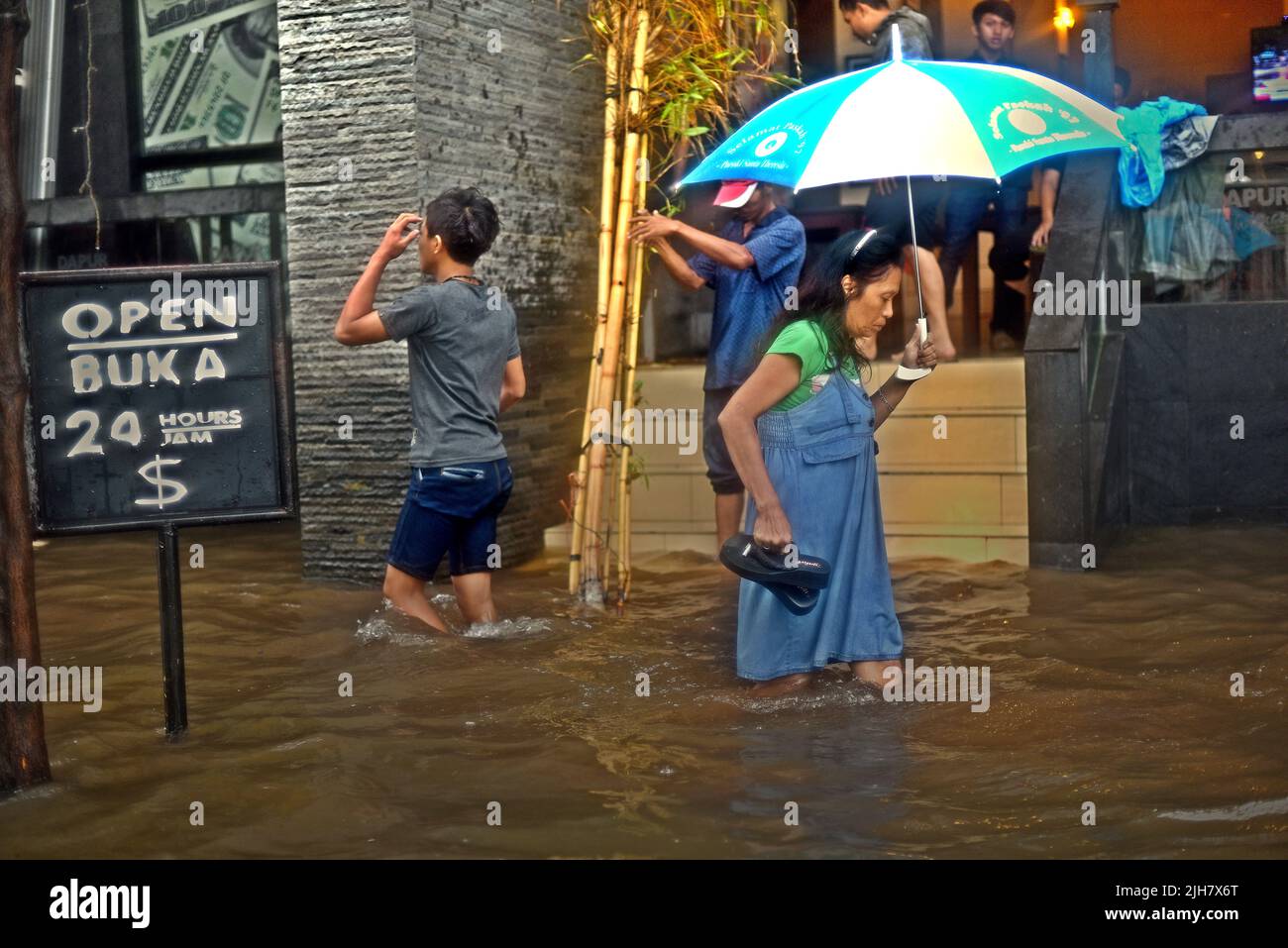 People walking through floodwater on the walkway of a commercial street ...